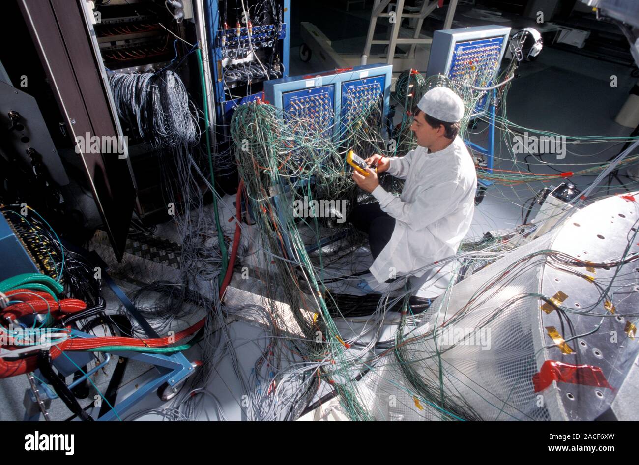 Satellite electronics testing. Engineer testing the electronics of a ...