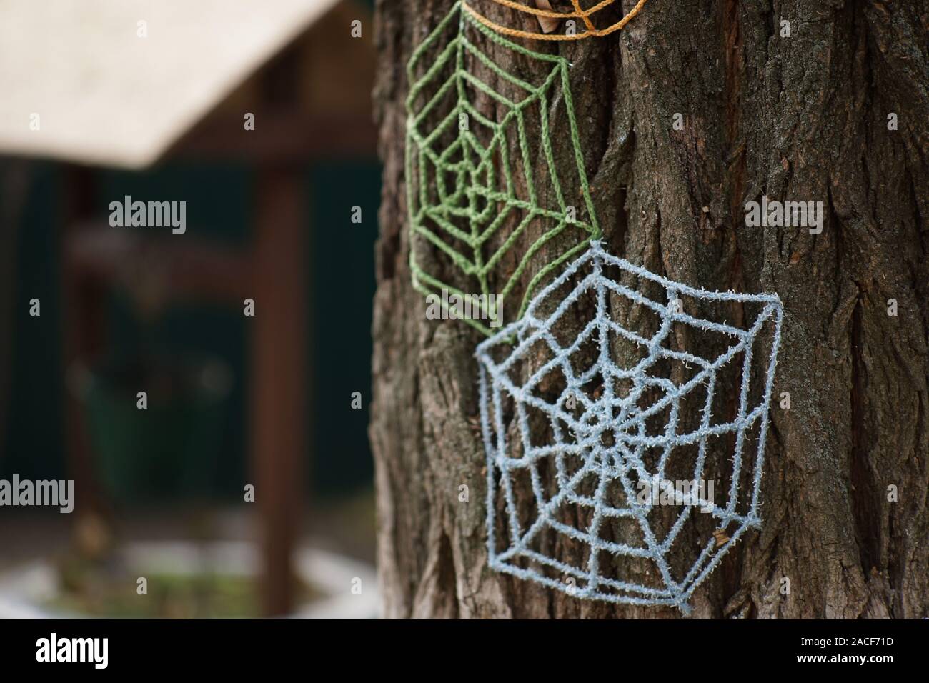 Blue and green knitted cobwebs on a tree trunk close-up Stock Photo - Alamy