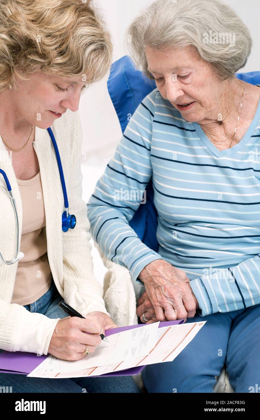 MODEL RELEASED. GP and elderly patient filling in a form Stock Photo ...