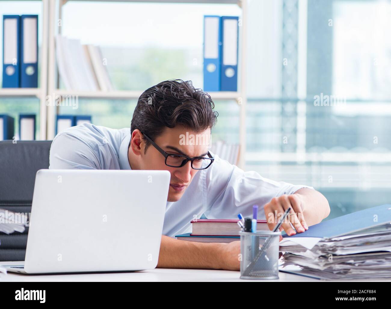 The businessman with excessive work paperwork working in office Stock ...