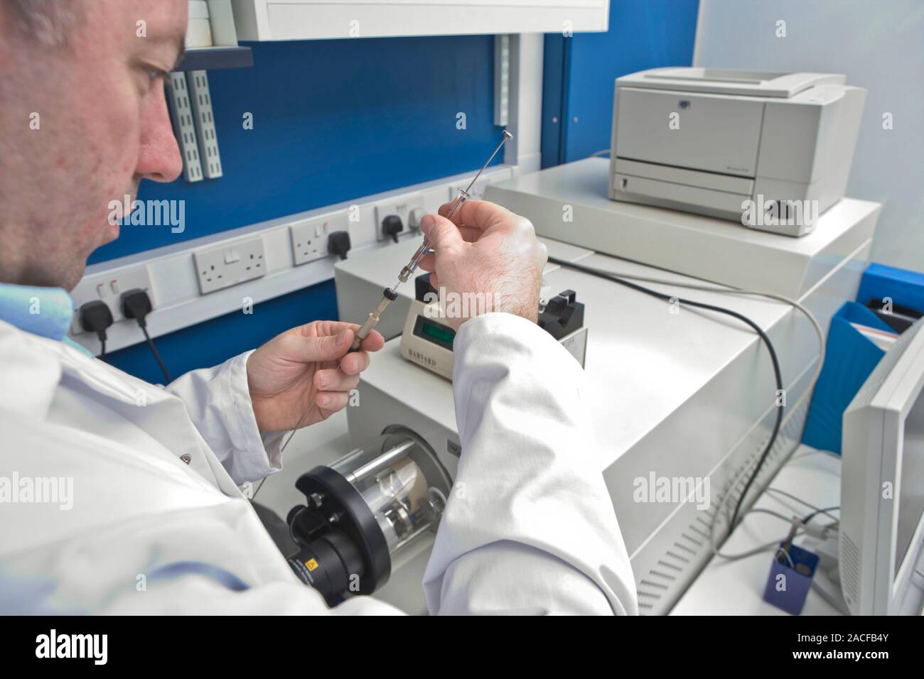 Protein analysis. Researcher using a nanospray needle to inject a ...