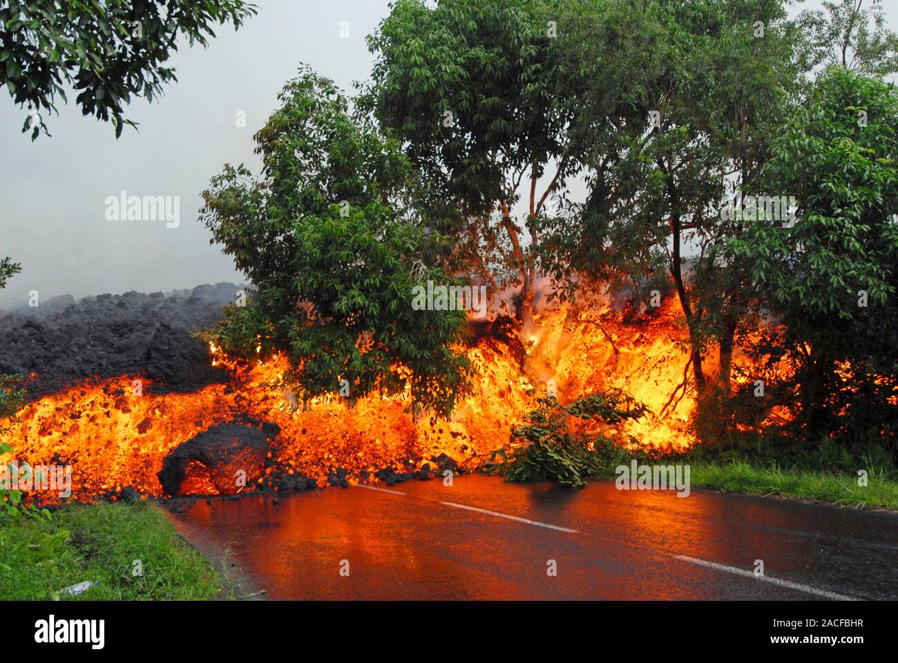 Volcanic eruption. Lava flow crossing a road during volcanic activity ...