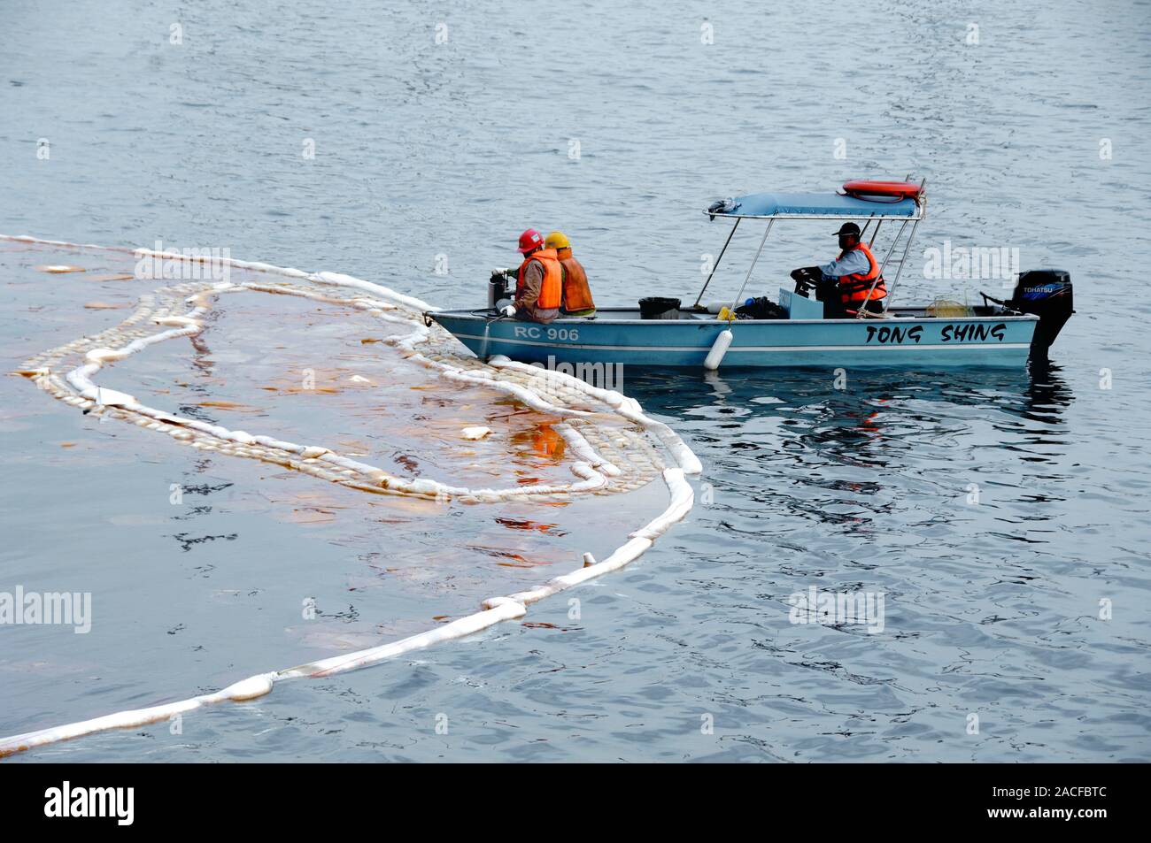 Oil spill cleanup. Workers on a boat helping to clean up an oil spill ...