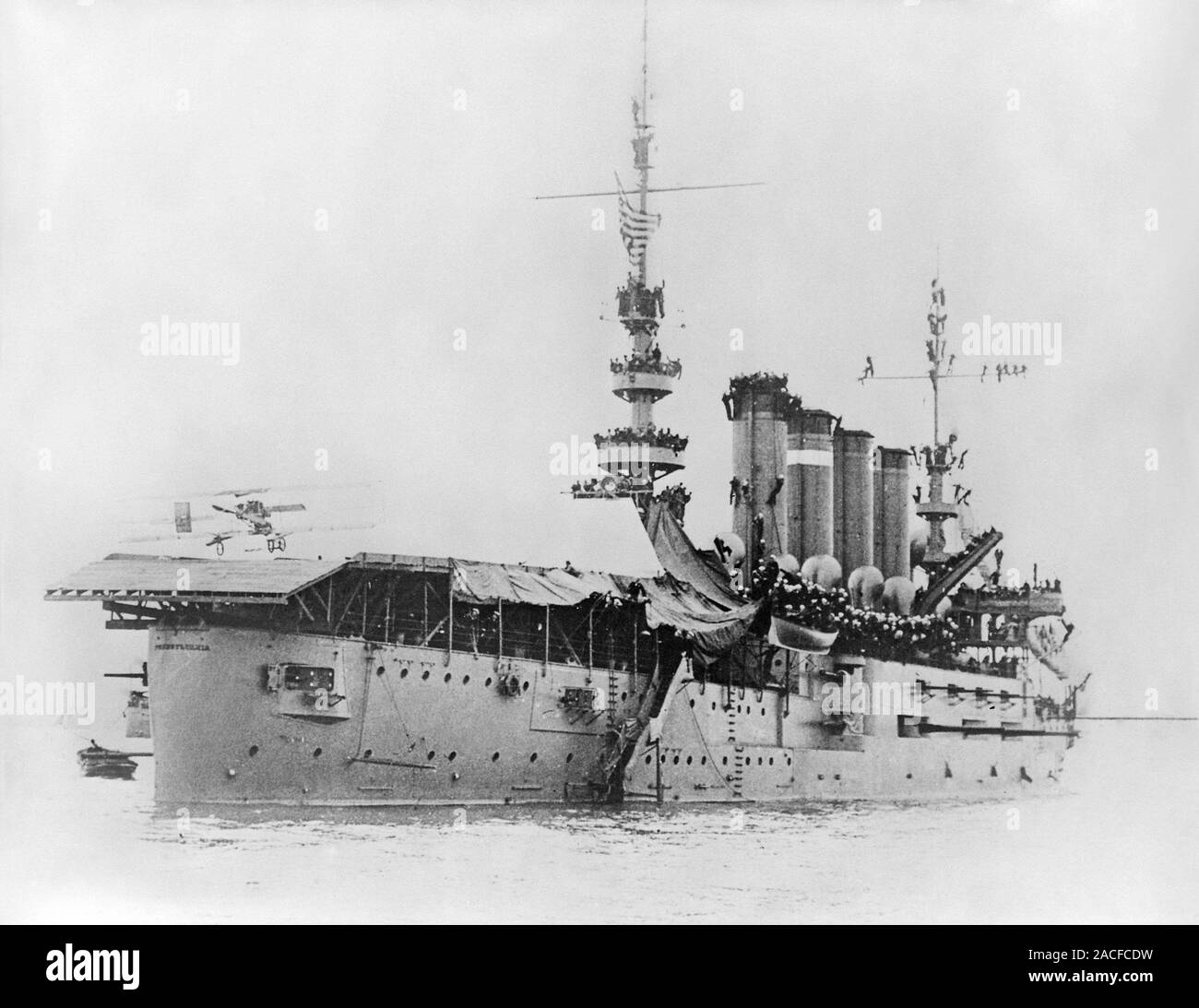 First aircraft landing on a ship, with crowds of sailors watching. The ...