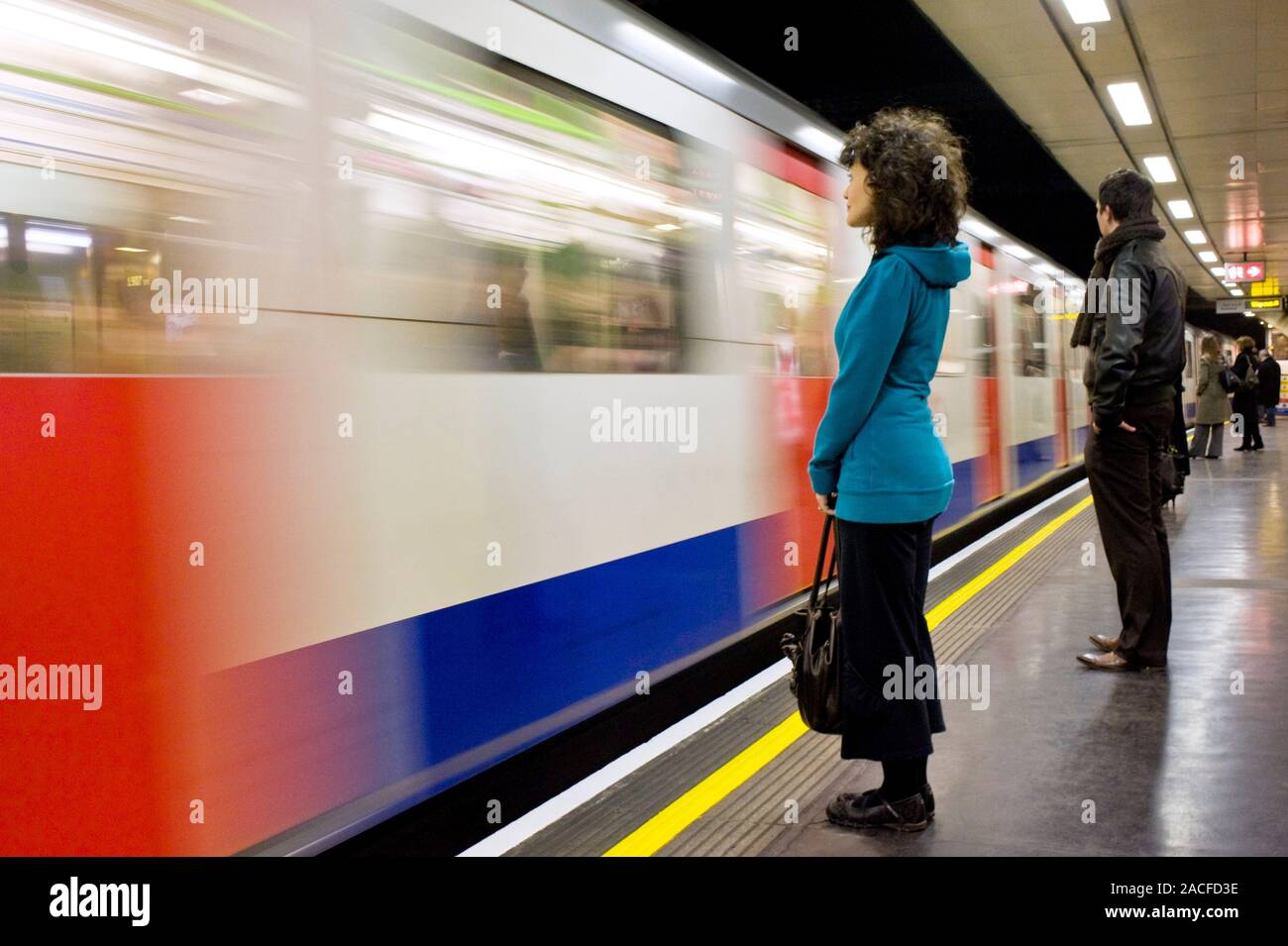 London Underground platform. Passengers waiting as a tube train enters ...