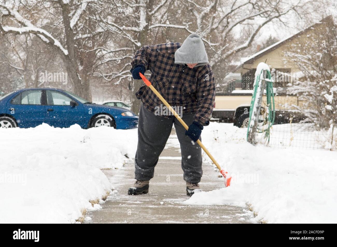 Snow clearing. Person clearing snow from a pavement shortly after a ...