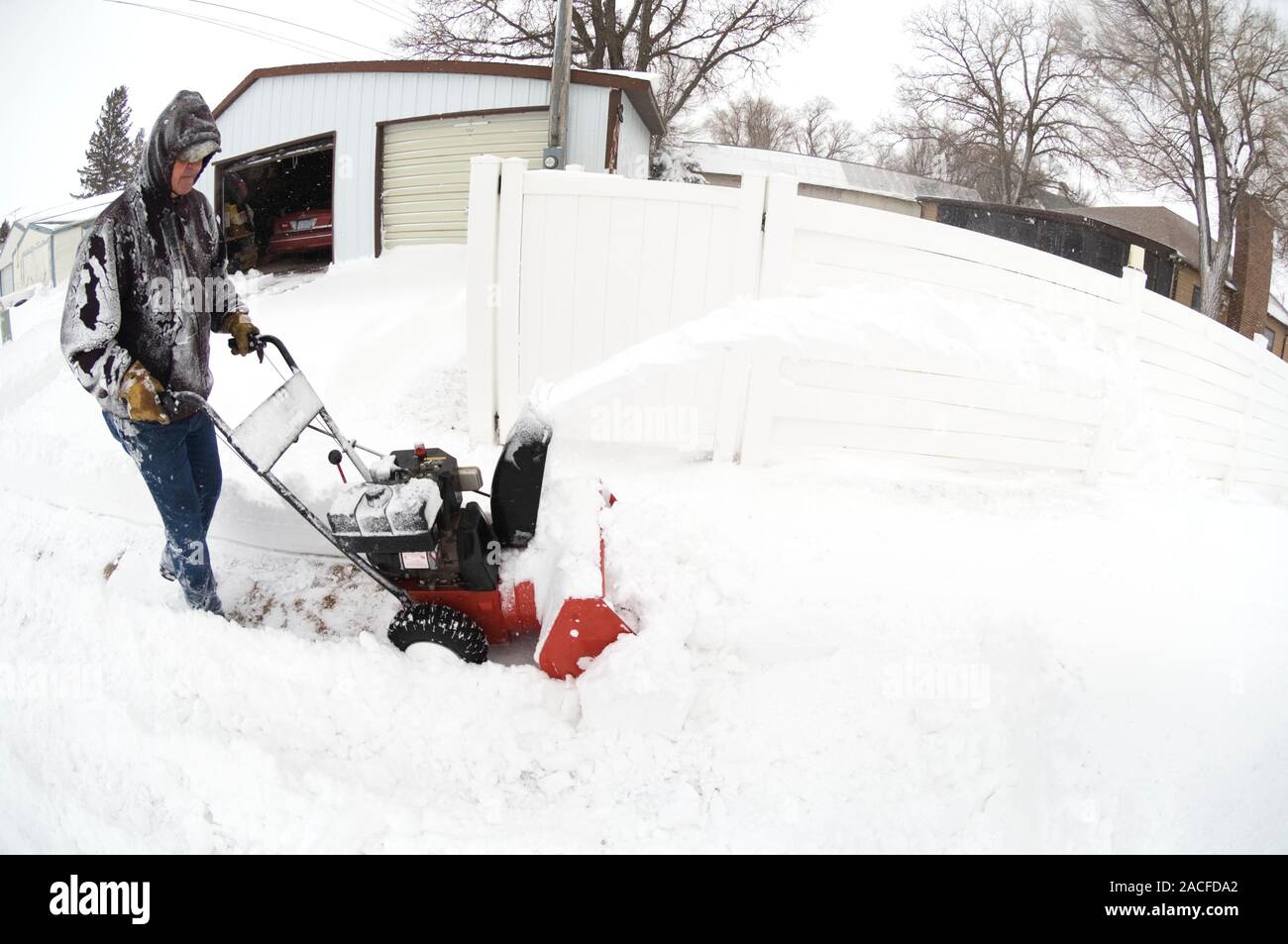 Snow clearing. Man pushing a snow-blower in an effort to remove snow ...