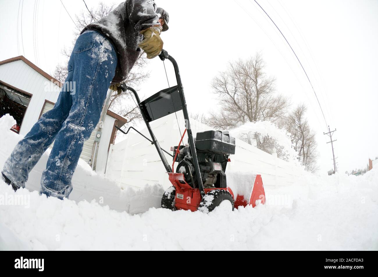 Snow clearing. Man pushing a snow-blower in an effort to remove snow ...