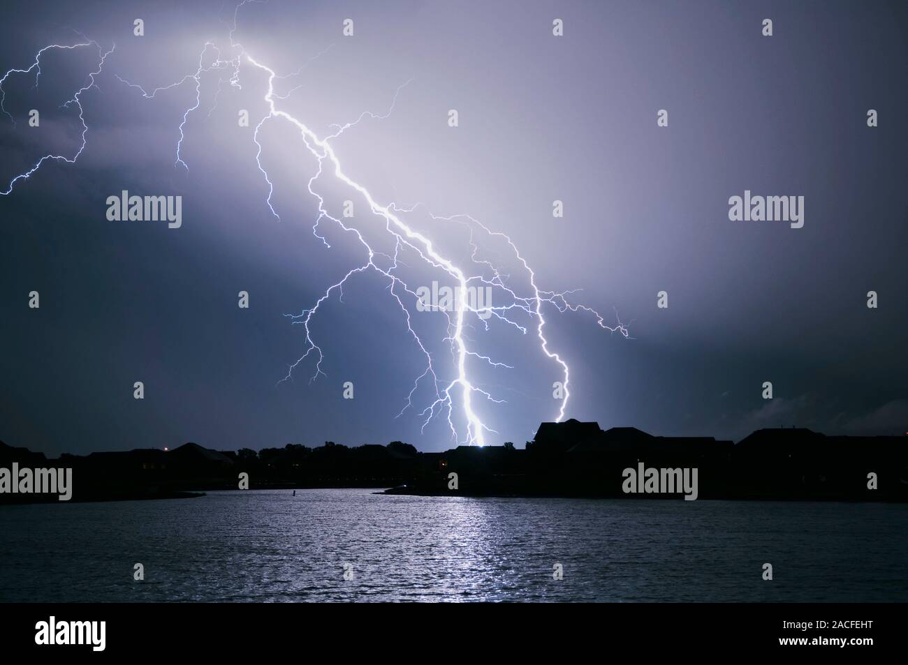 Lightning bolts striking near houses by a lake. Photographed in Wichita ...