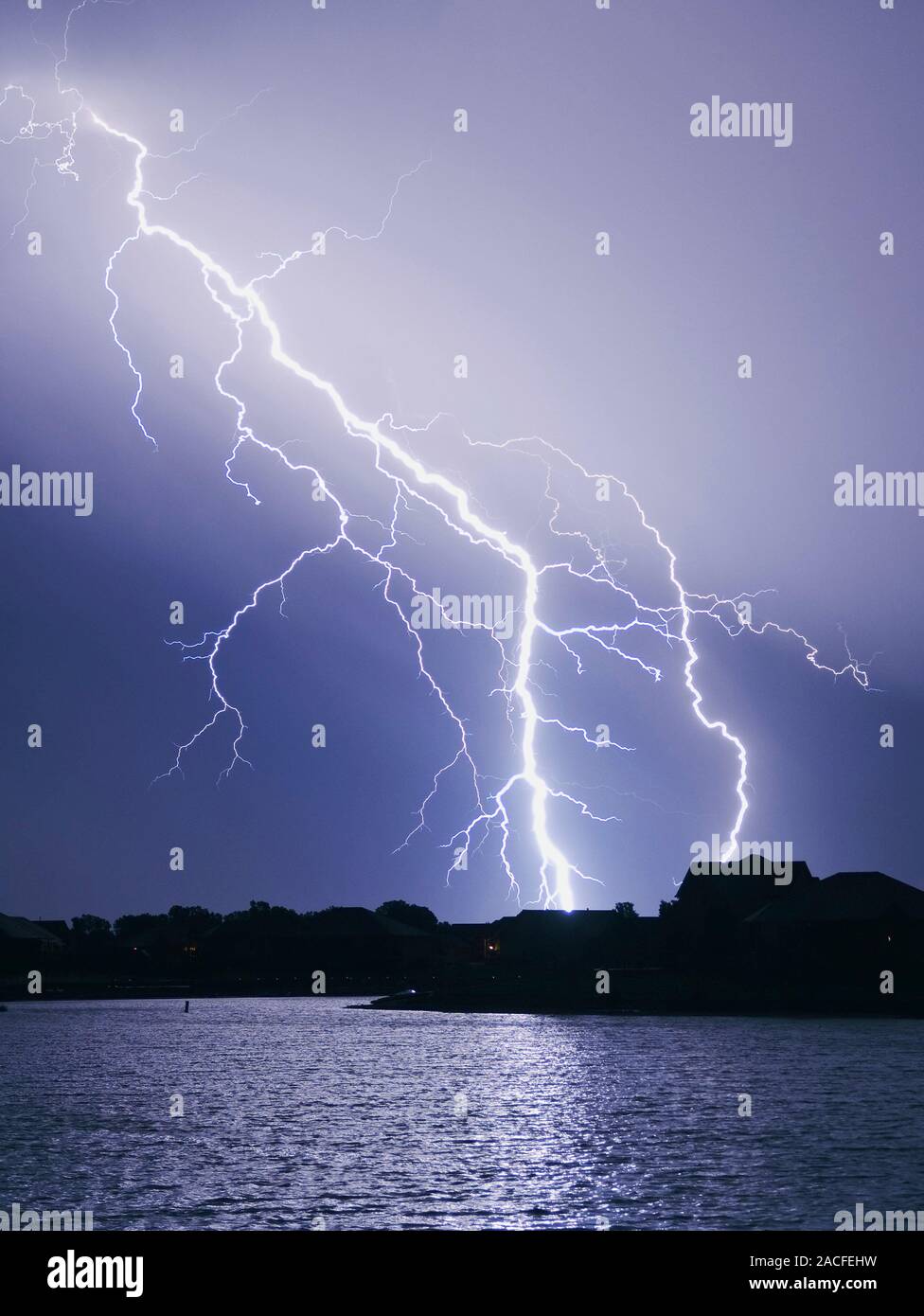 Lightning bolts striking near houses by a lake. Photographed in Wichita ...
