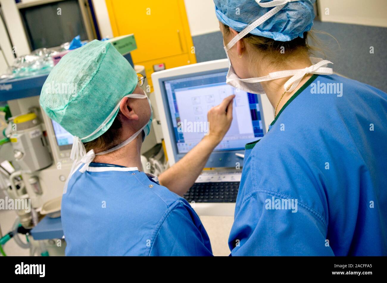 Monitoring a patient. Anaesthetists checking a patient's vital signs on ...