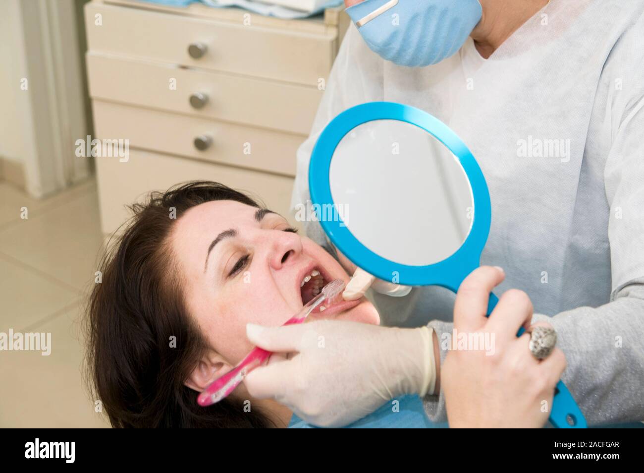 Dental examination. Dental hygienist showing a woman how to brush her ...