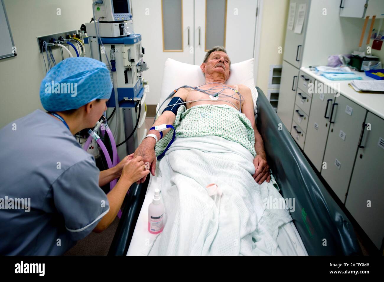 Anaesthetising a patient. Anaesthetist inserting a cannula into the ...