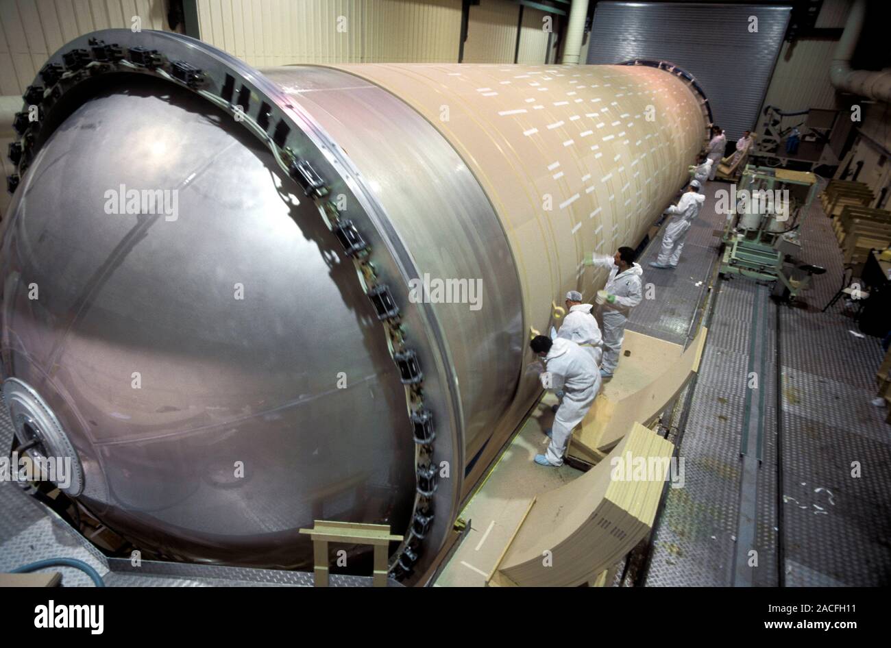 Ariane 5 cryogenic tank production. Workers apply insulating tiles onto ...