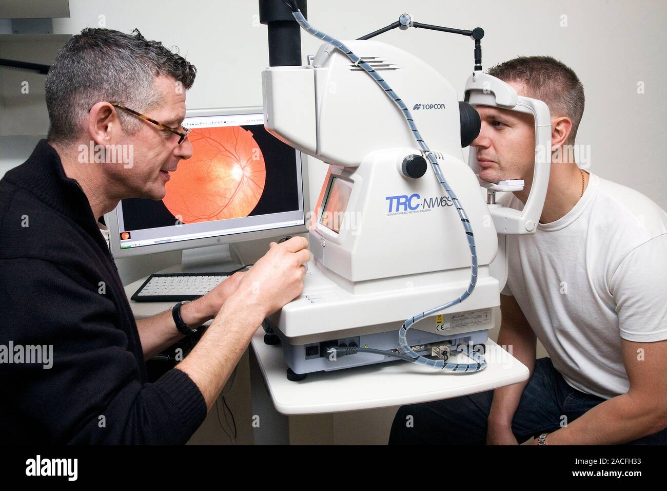 Eye examination. Ophthalmologist using a fundus camera to examine a ...