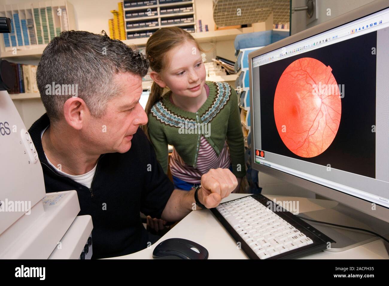 Eye examination. Ophthalmologist (left) and patient looking at an image ...