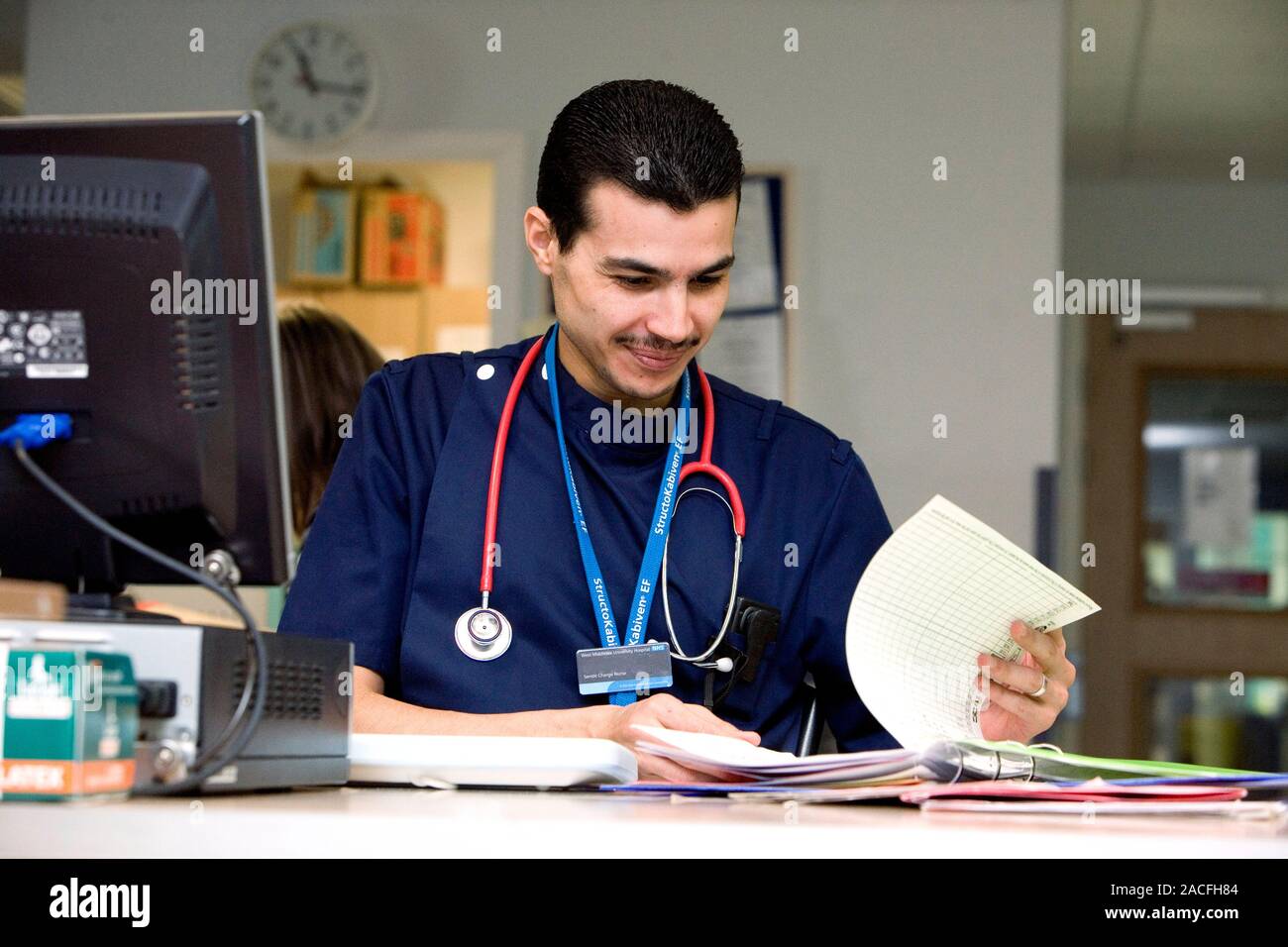 Senior nurse entering patient notes into a computer database ...