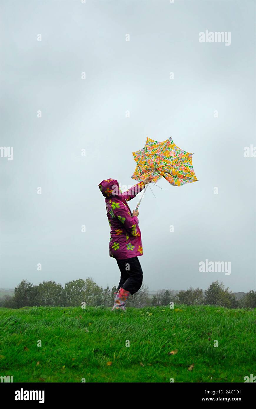 Wet and windy weather. Woman wearing a waterproof coat and holding an ...