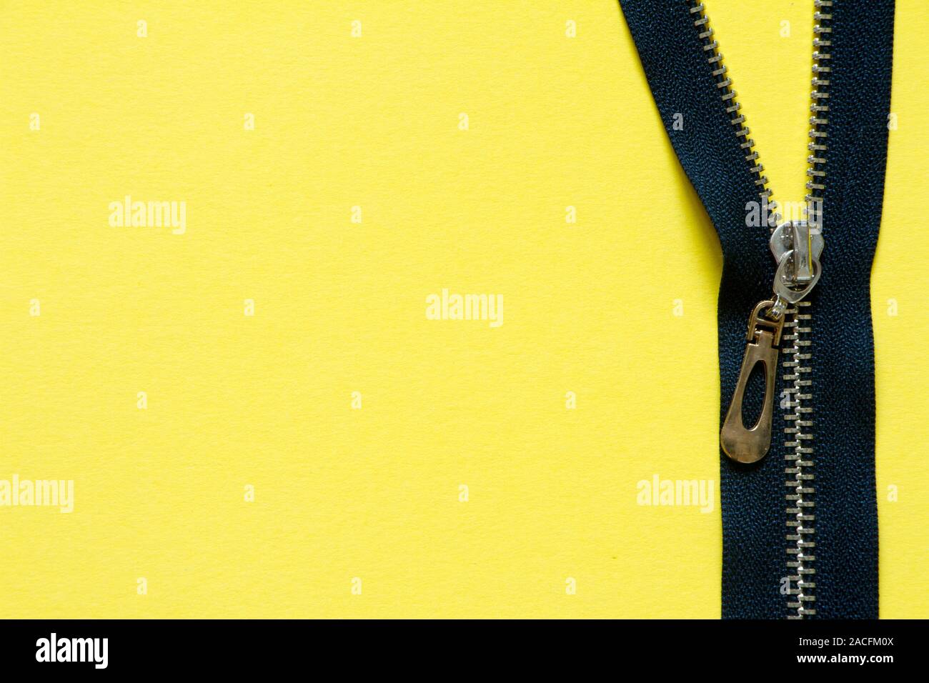 Open zipper clasp with a golden slider on a yellow background ...