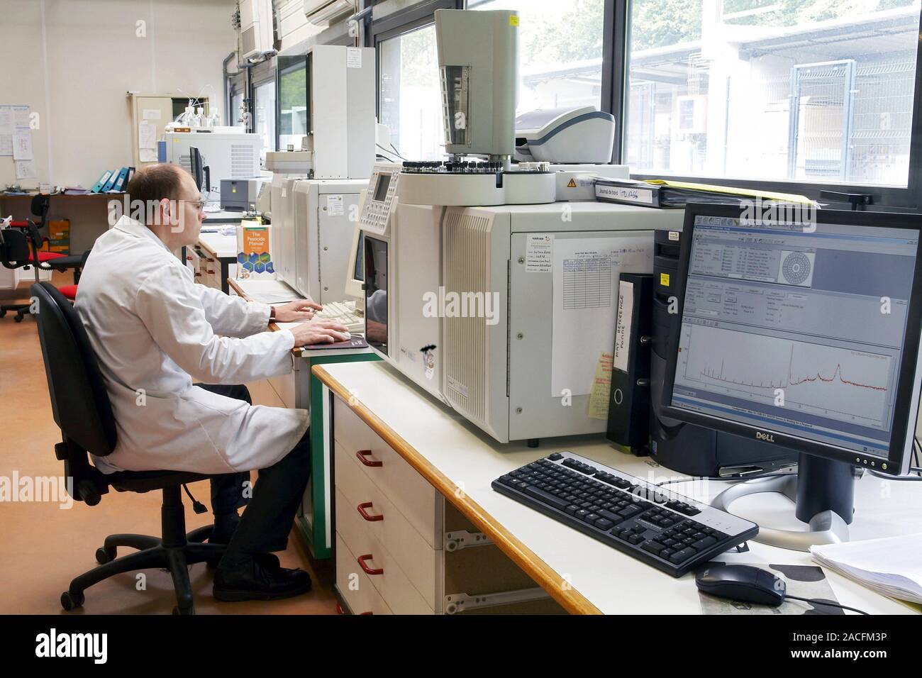 Food analysis. Researcher using a chromatography machine (centre) to ...