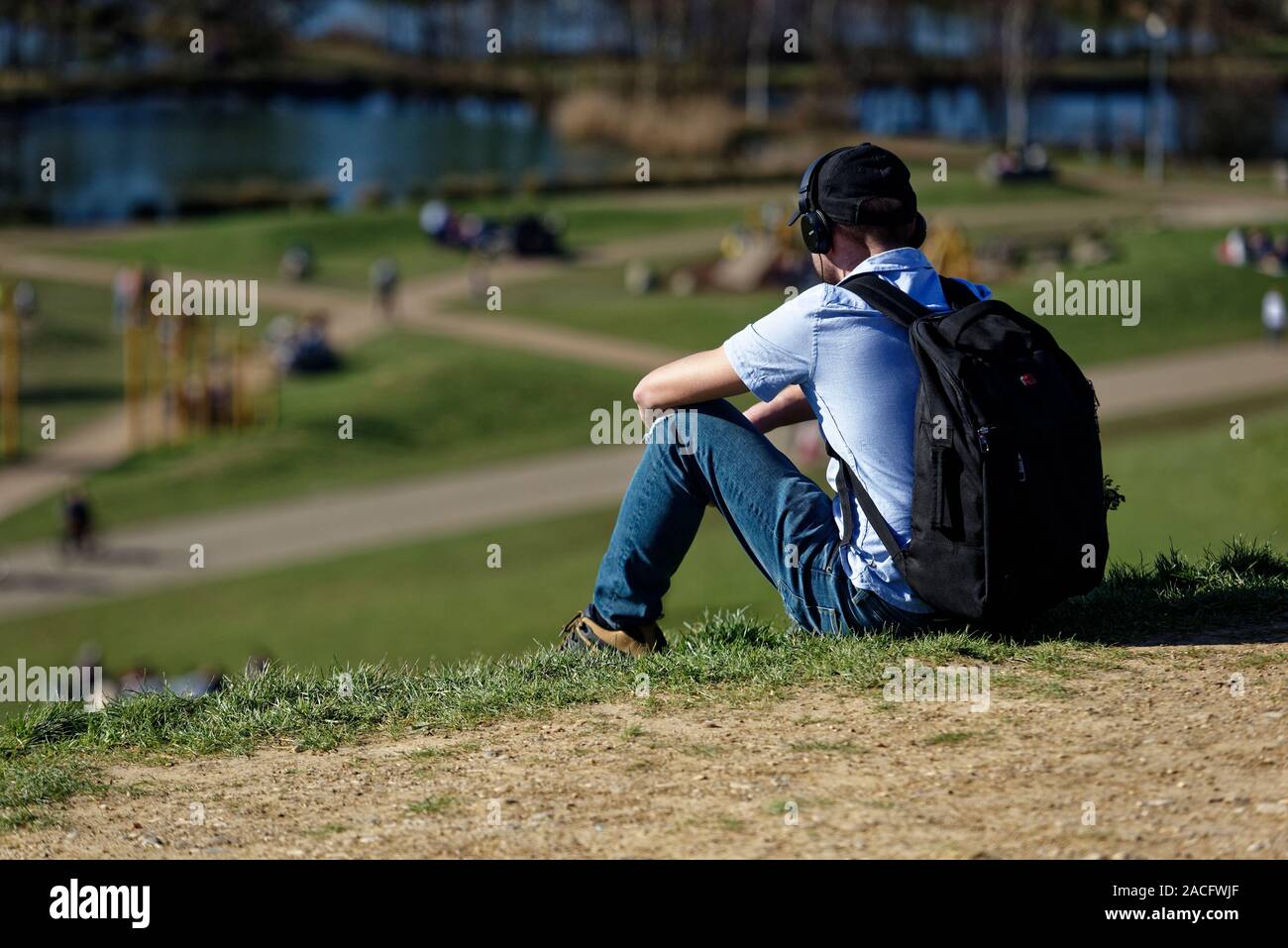 Man sitting on slope looking across Northala Park, Northolt, shallow ...