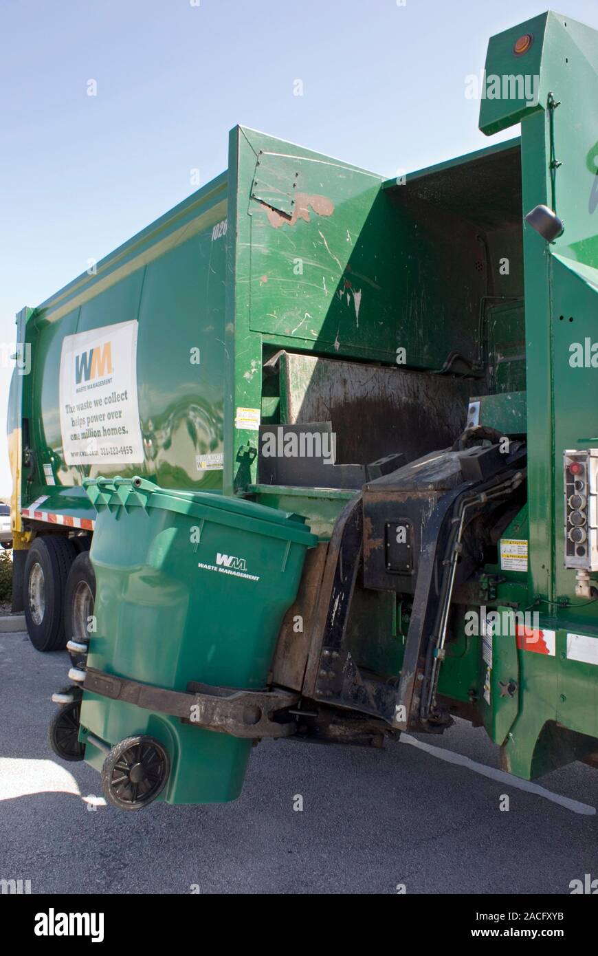 Refuse collection vehicle lifting a wheelie bin. Photographed in ...