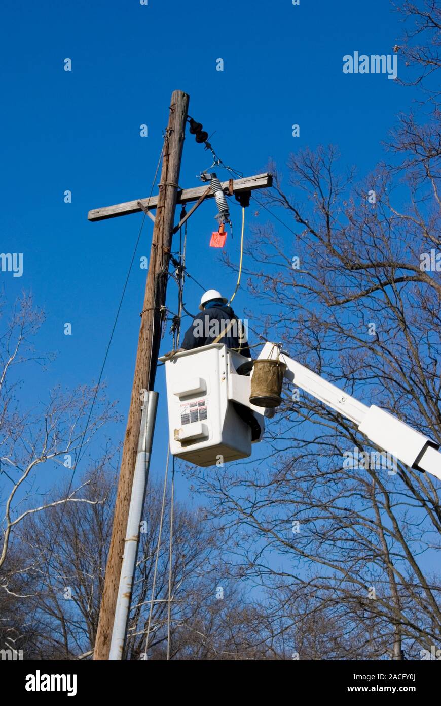 Power line maintenance. Technician in a cherry picker maintaining an ...