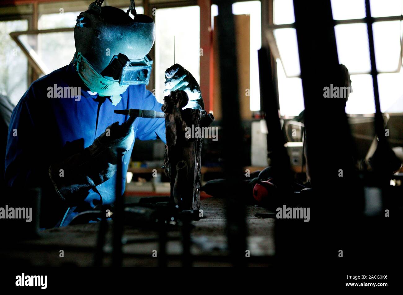 Metalworker sculpting bronze using a blowtorch while wearing protective ...