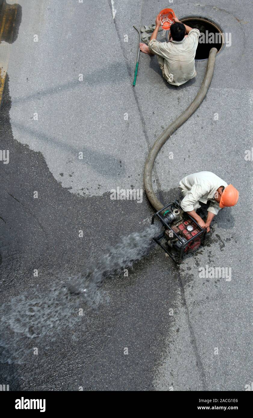 Street workers pumping water. Pumping machine being used by street ...