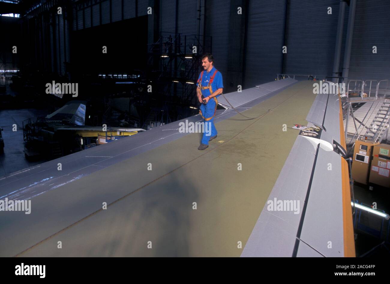 Passenger aircraft construction. Worker wearing a safety harness ...