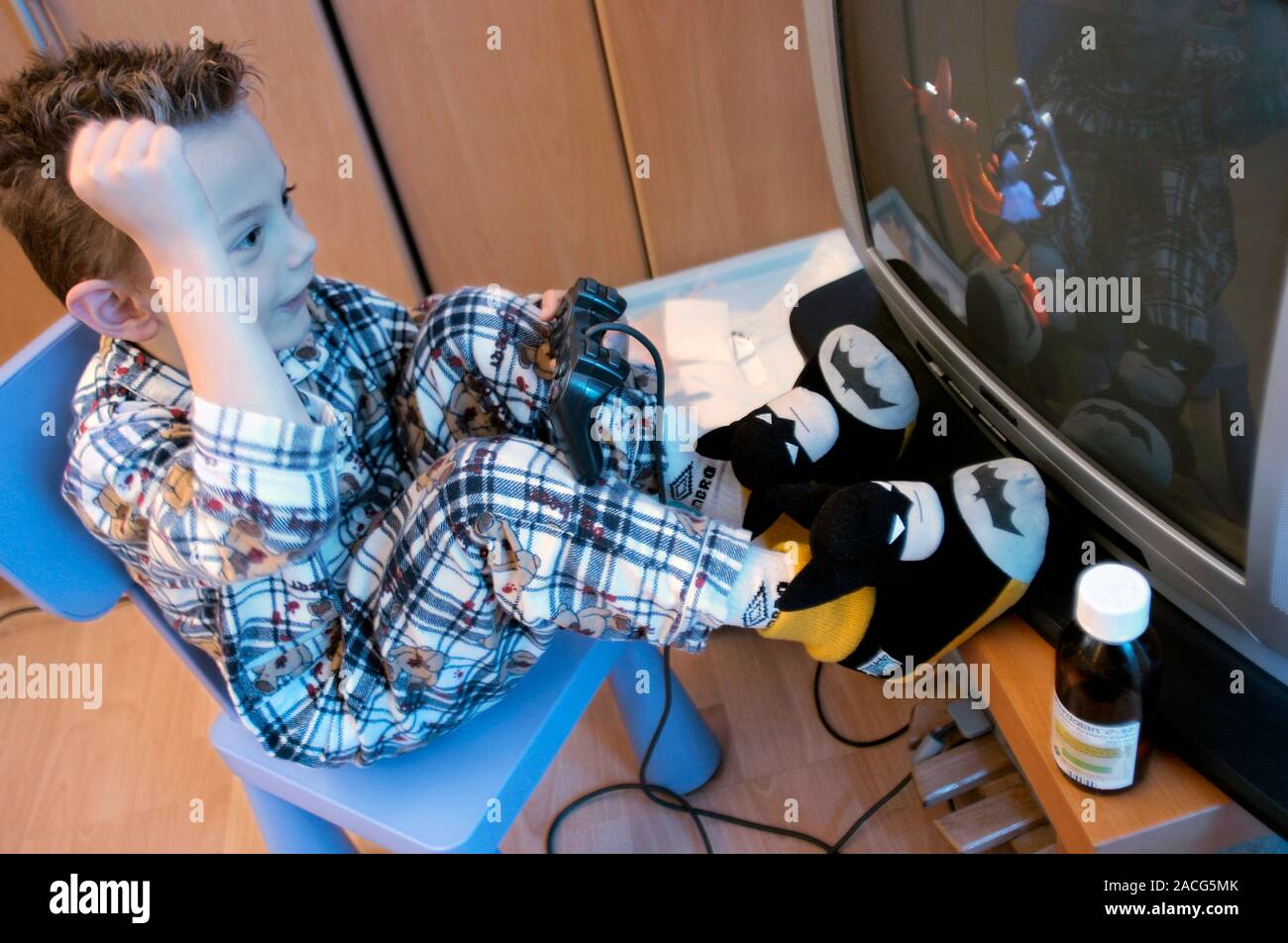 Sick child playing a games console in his pyjamas Stock Photo - Alamy
