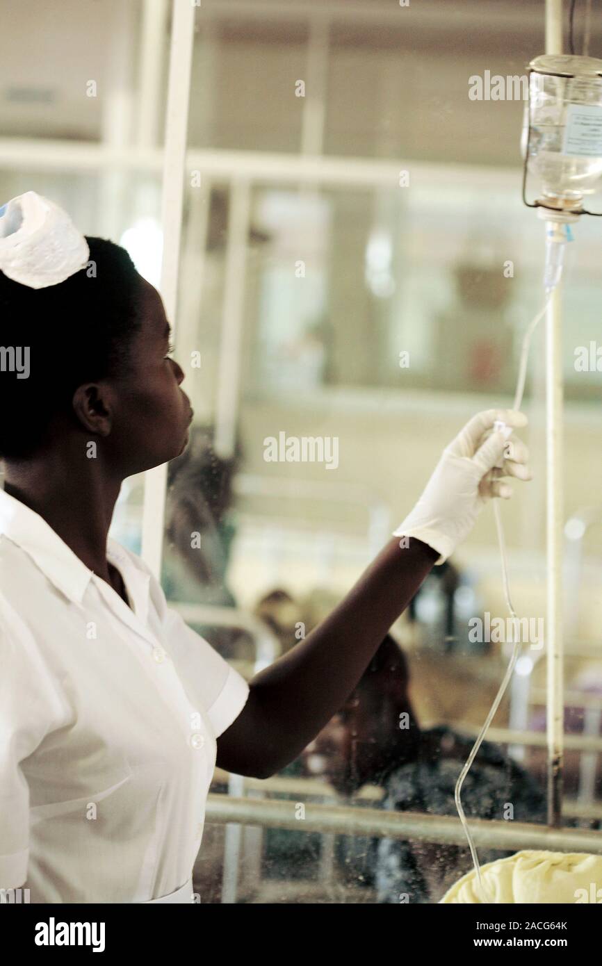 Hospital nurse adjusting a patient's saline drip in a hospital ward ...