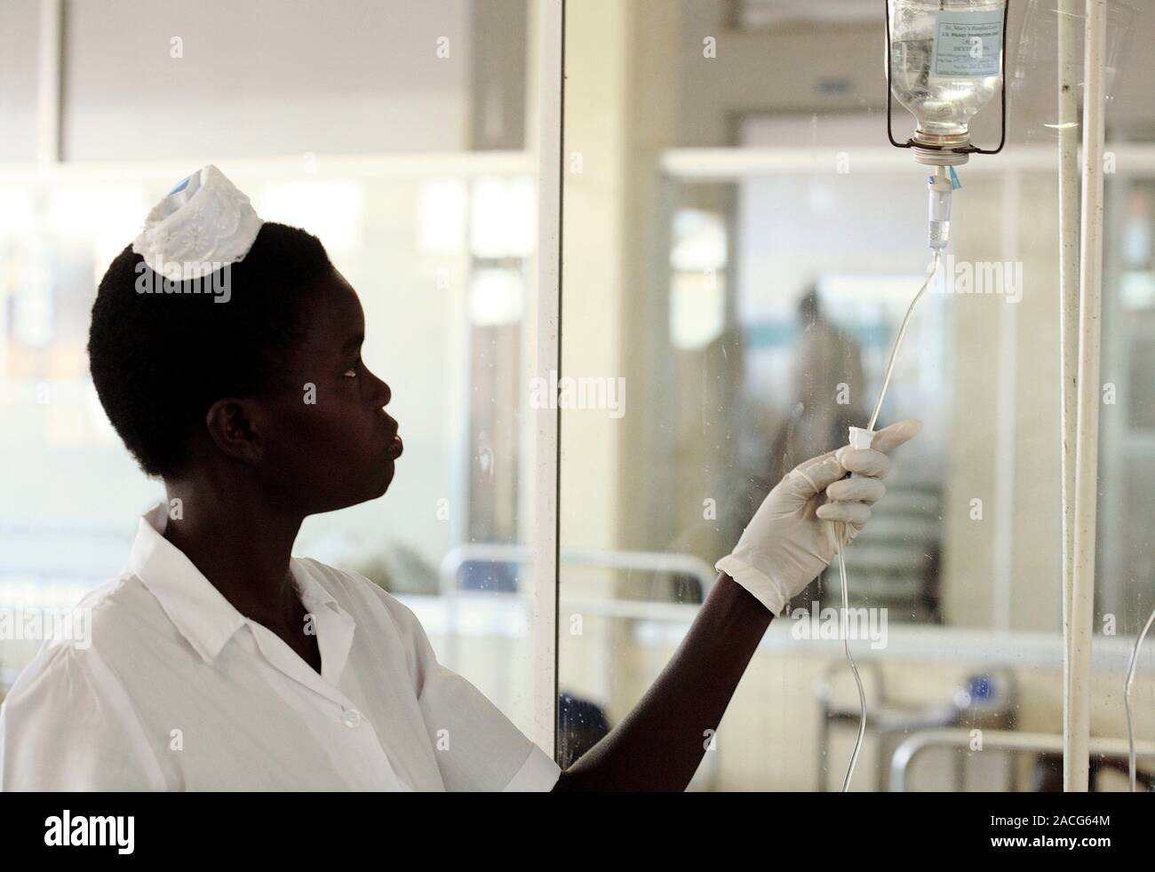 Hospital nurse adjusting a patient's saline drip in a hospital ward ...