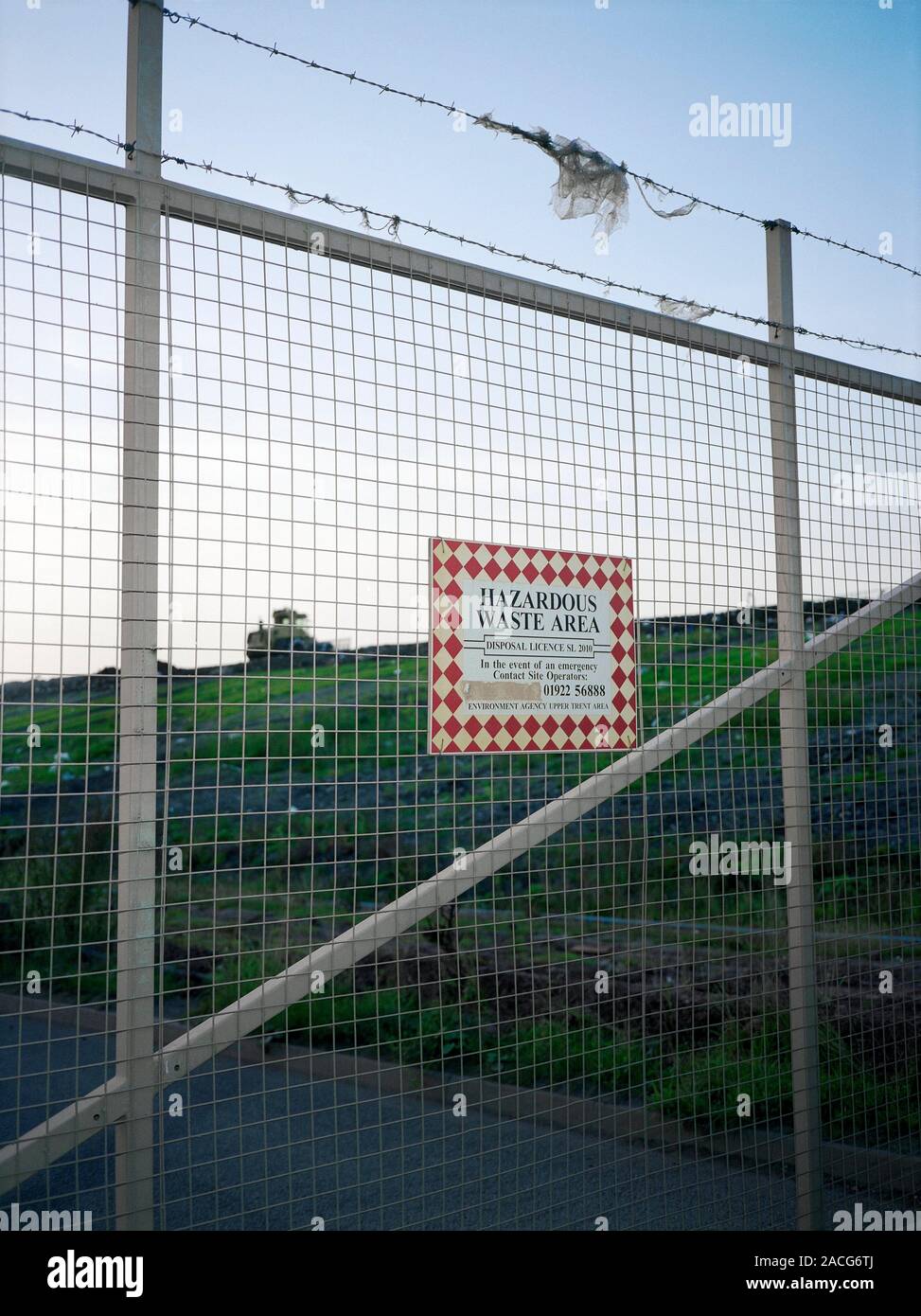 Hazardous waste area sign on a fence at a landfill site, Aldridge, West ...
