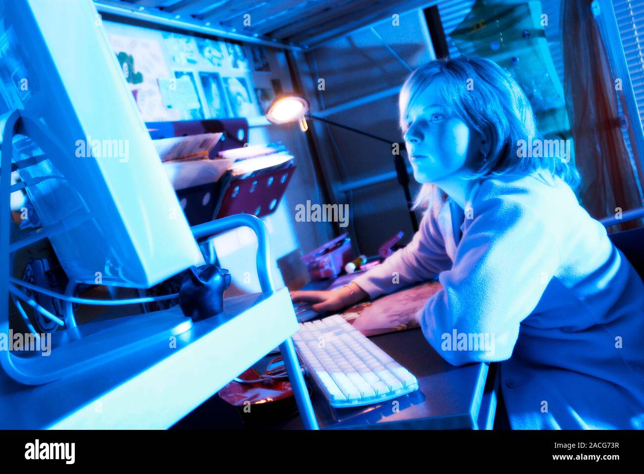 Teenager using a computer. Teenage girl sitting at a desk with a ...