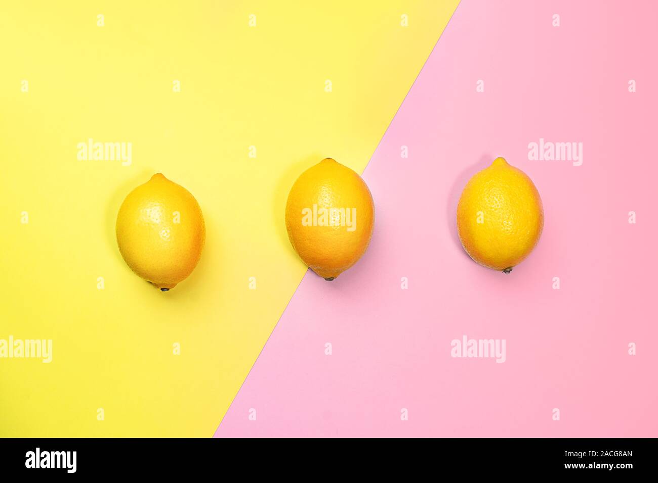 Creative pattern made of lemons on bright yellow and pastel pink ...