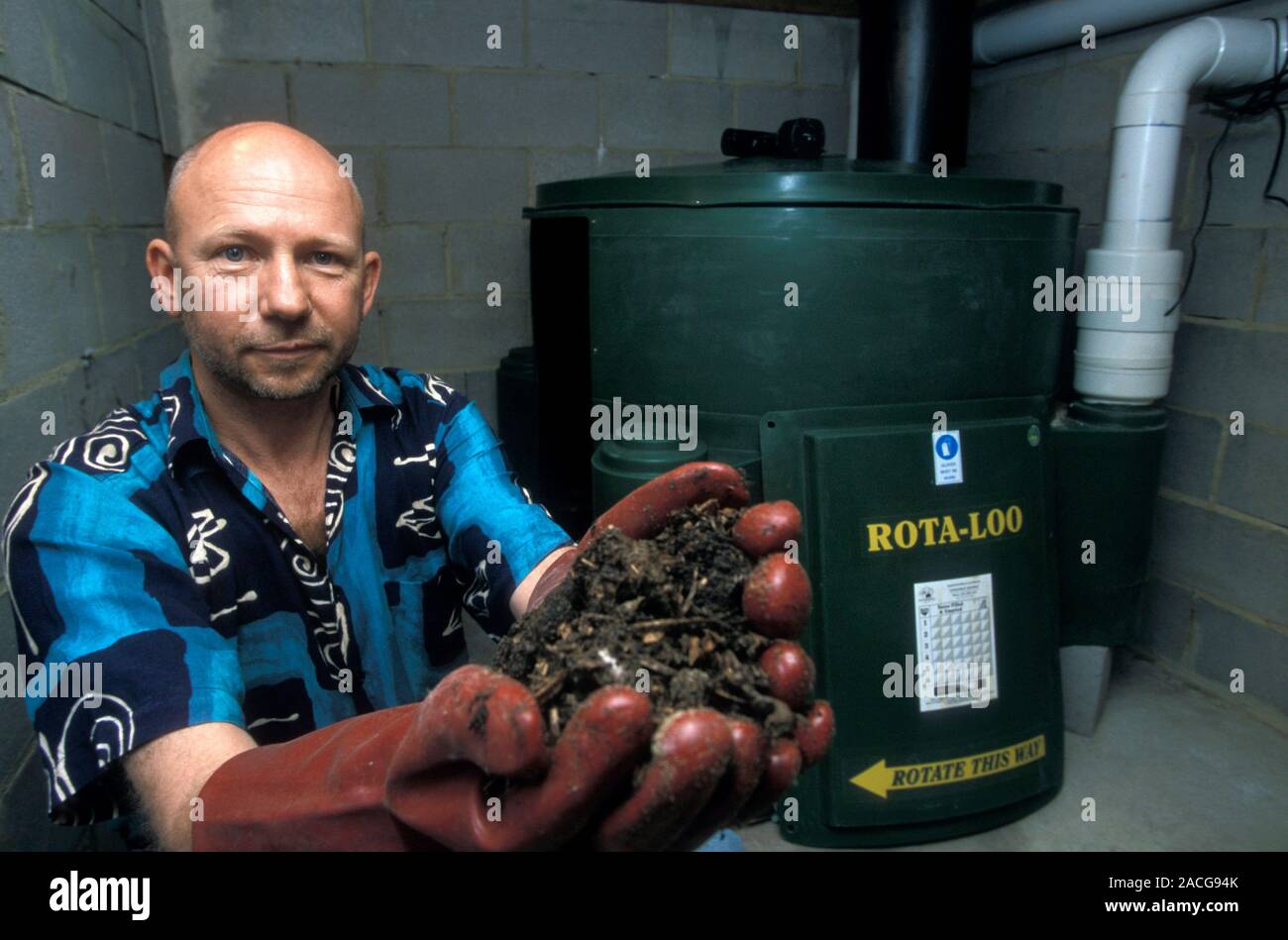 Composting toilet. Inventor Buzz Burrows holding out an example of ...