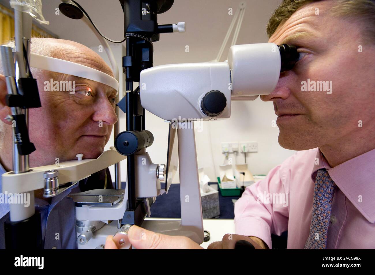Eye examination using a slit lamp. This instrument shines a fine beam ...