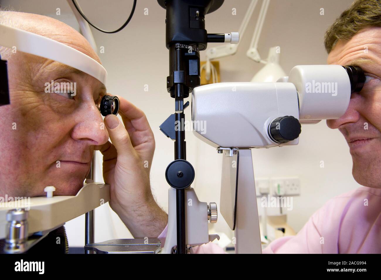 Eye examination. Ophthalmologist using a magnifying glass to examine a ...
