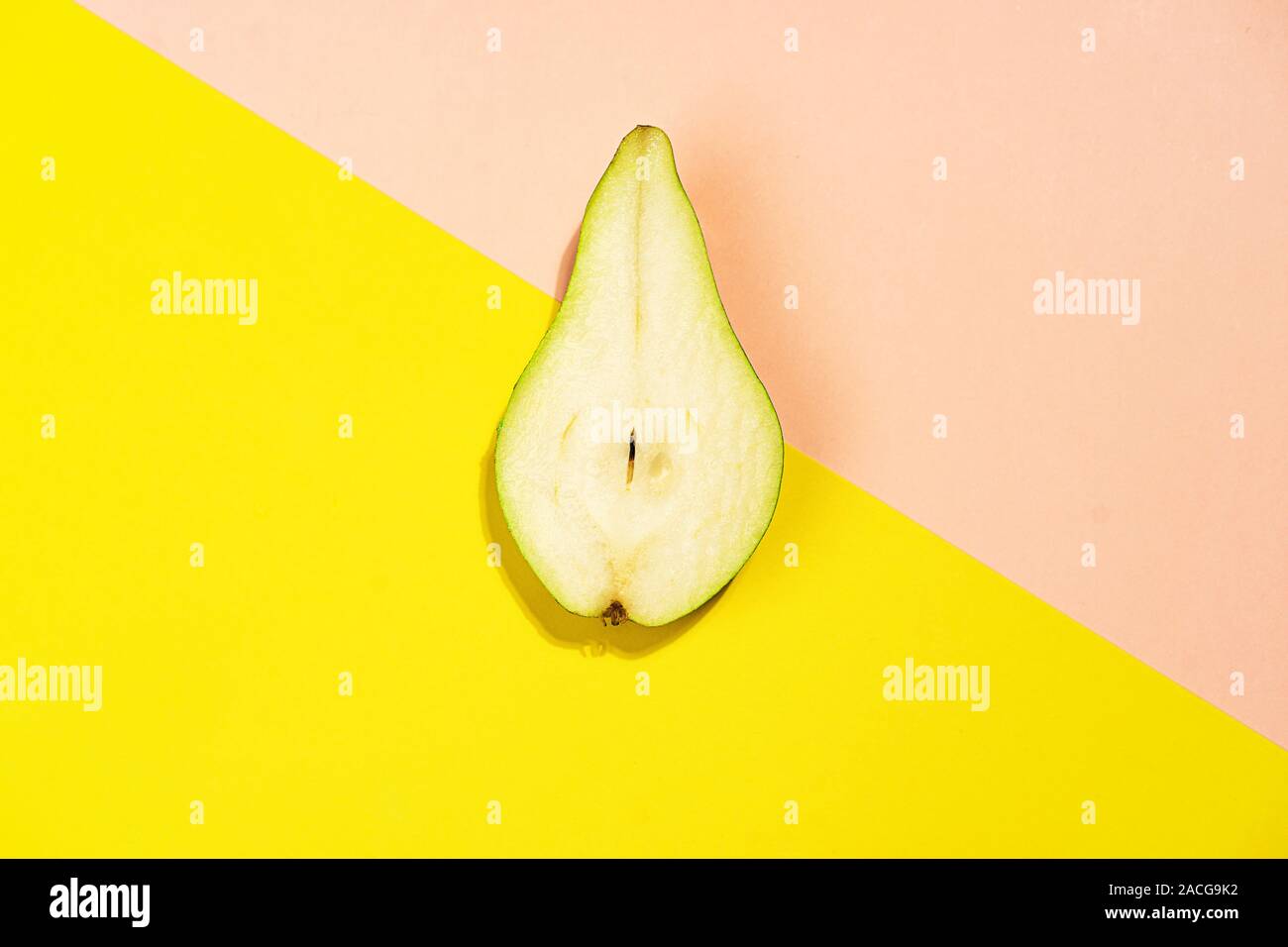 Creative pattern made of half pear on bright yellow and pastel pink ...