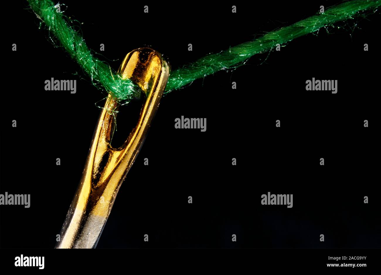 Eye of a needle and thread. Close-up of a piece of thread (green ...