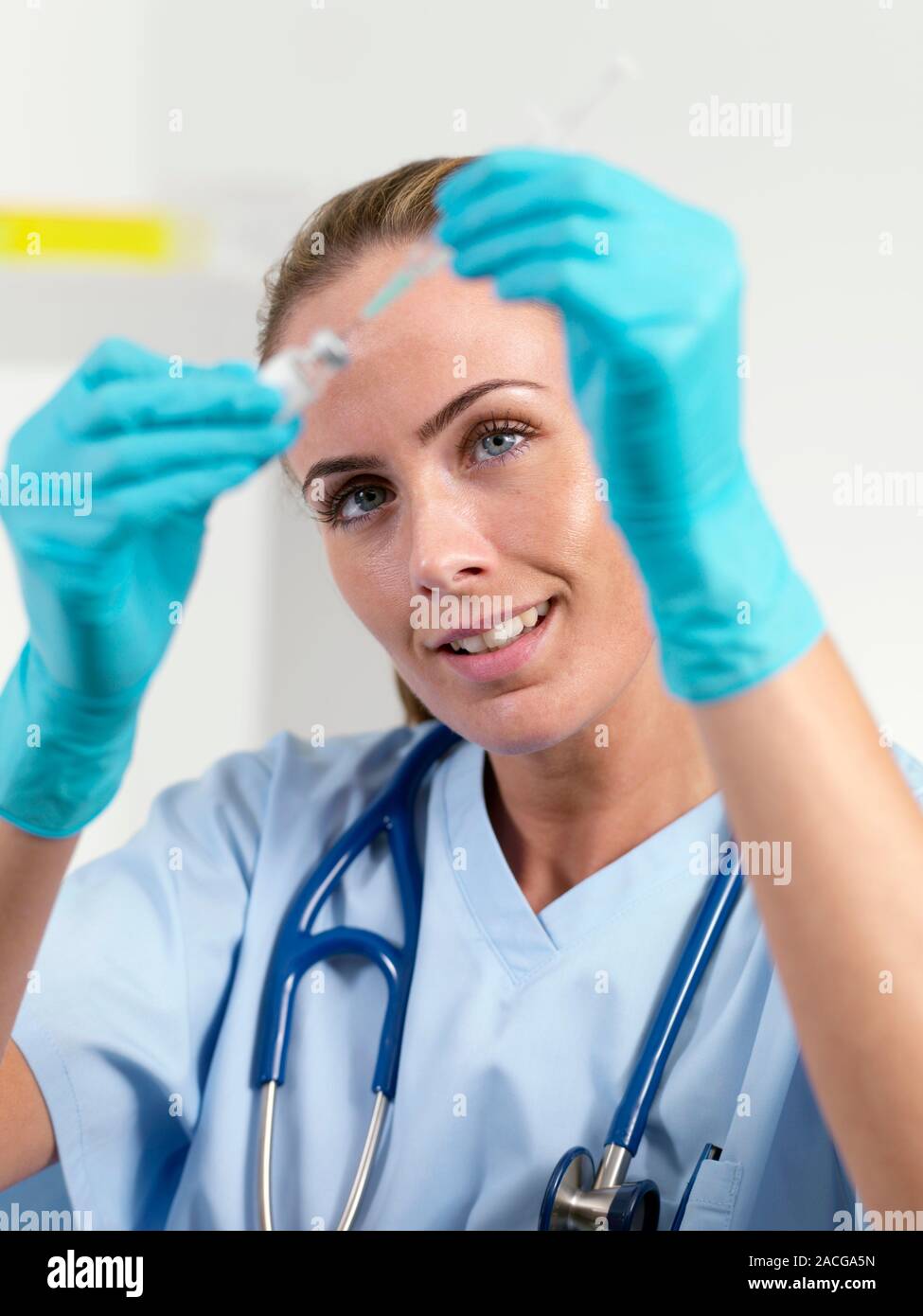 Nurse preparing an injection. Nurse holding up a syringe and vial, and ...