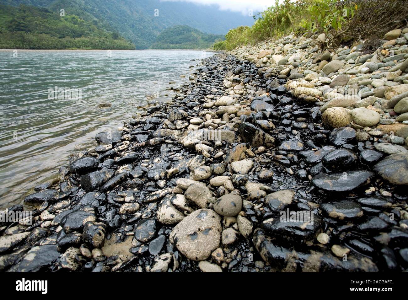 Oil spill in the Amazon. Oil slick on pebbles beside a river in the ...