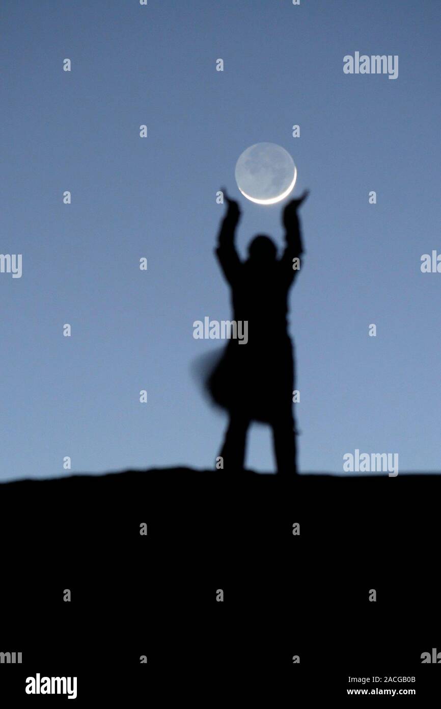 Playing with the Moon. Silhouetted human figure holding the crescent ...