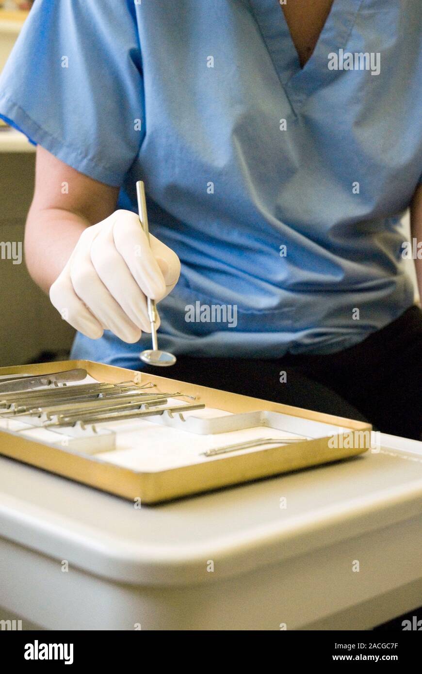 Dental instruments. Dentist picking up a mirror from a tray of dental ...