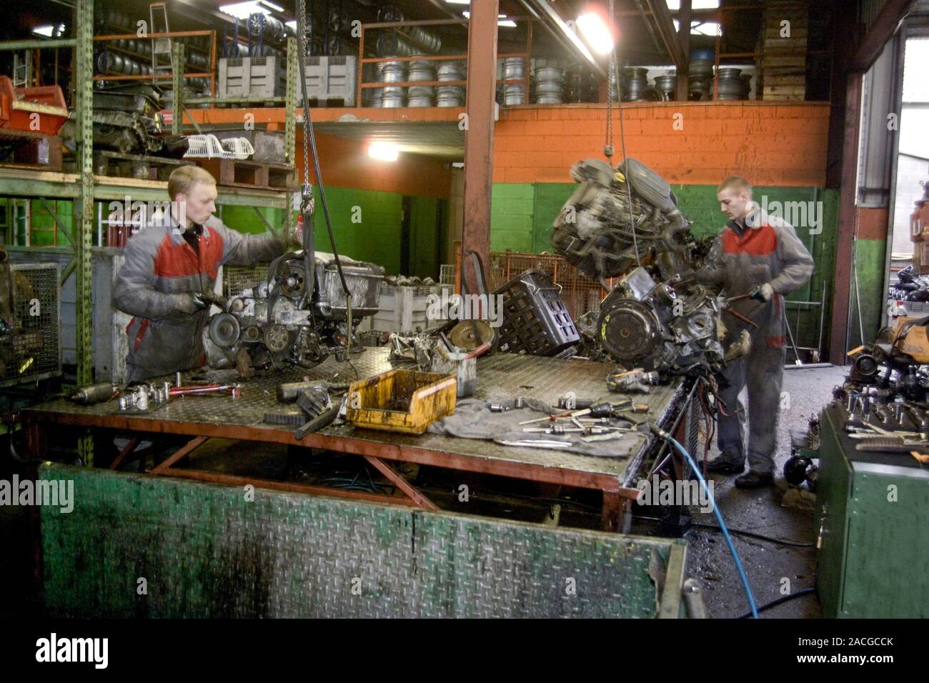 Car scrapyard. Scrapyard workers dismantling engines from scrapped ...