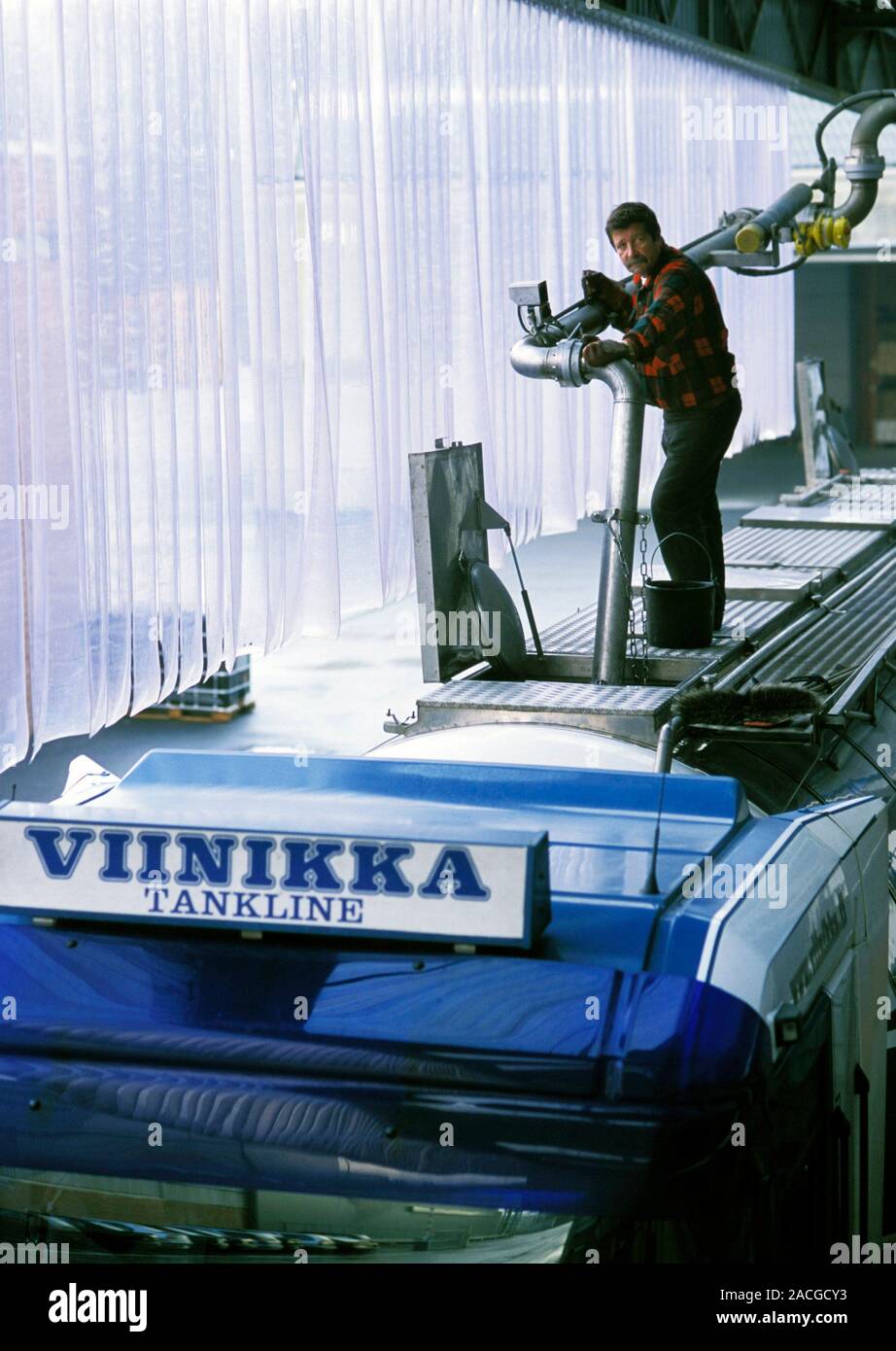 Oil refinery. Technician loading petroleum products into a tanker at a ...