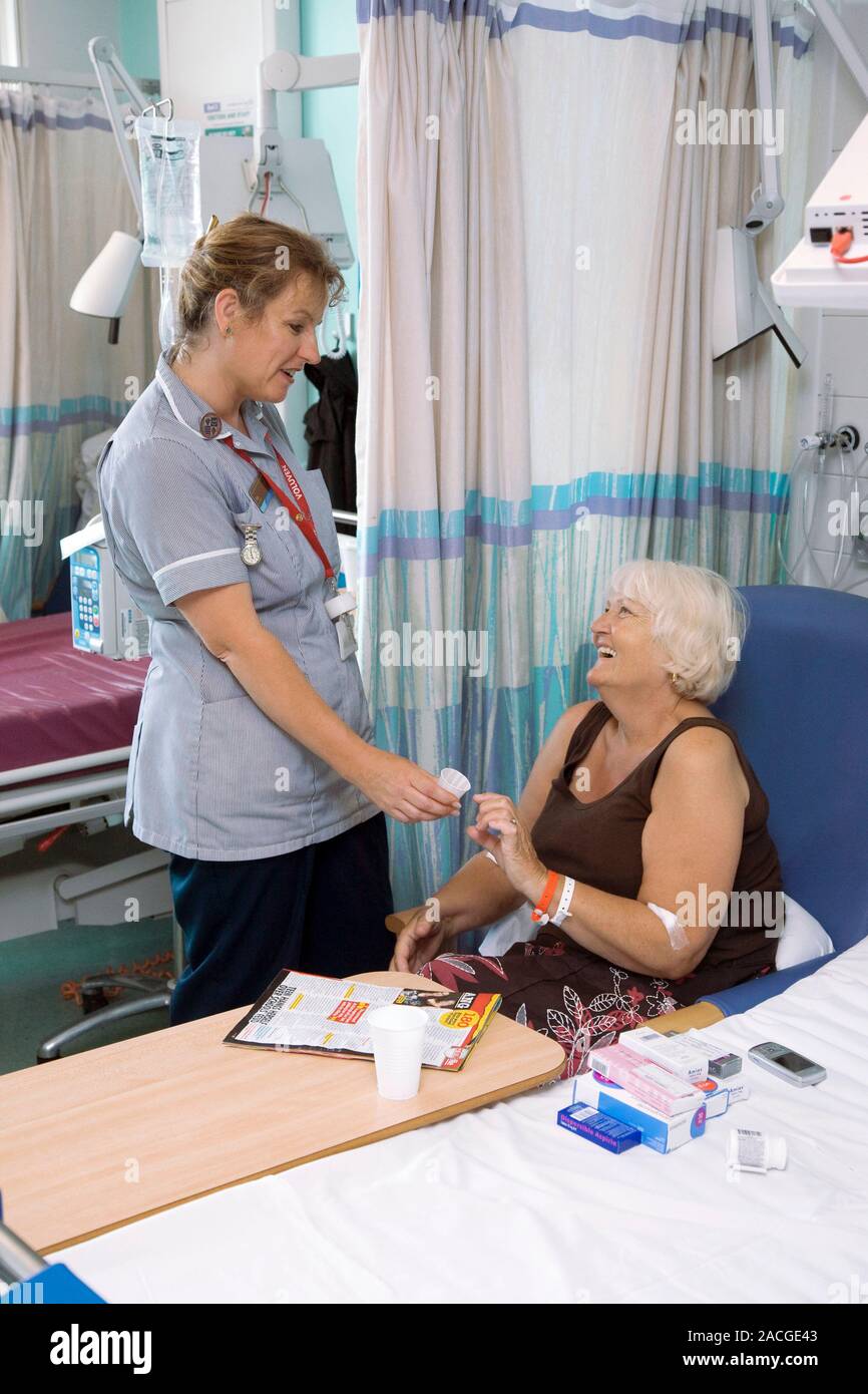 Nurse and patient. Staff nurse handing medicine to a patient on the ...
