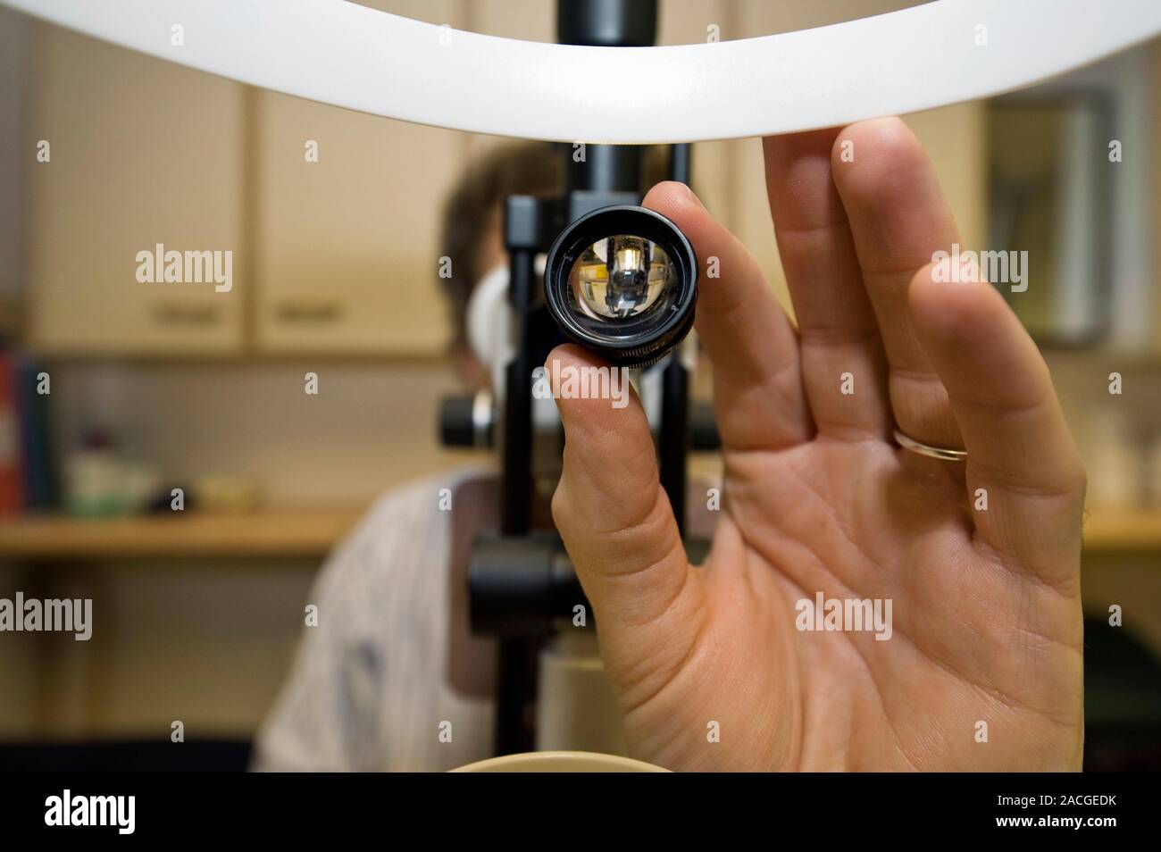 Hand of an ophthalmologist holding a lens and looking into a slit lamp ...