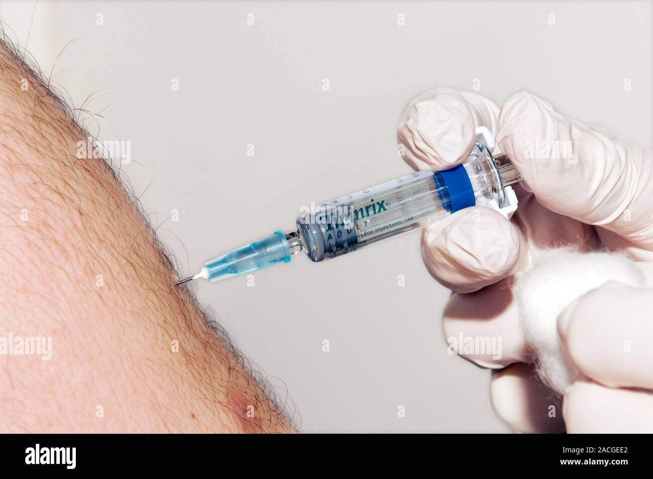 Gloved hand holding a syringe administers Twinrix vaccine to inoculate ...